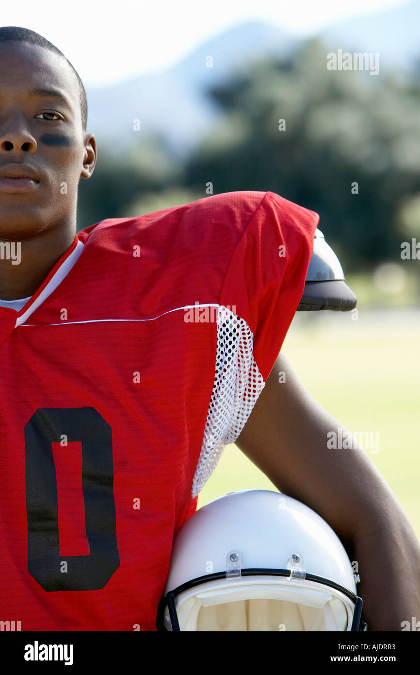 Football Player holding helmet on field, cropped Stock Photo - Alamy