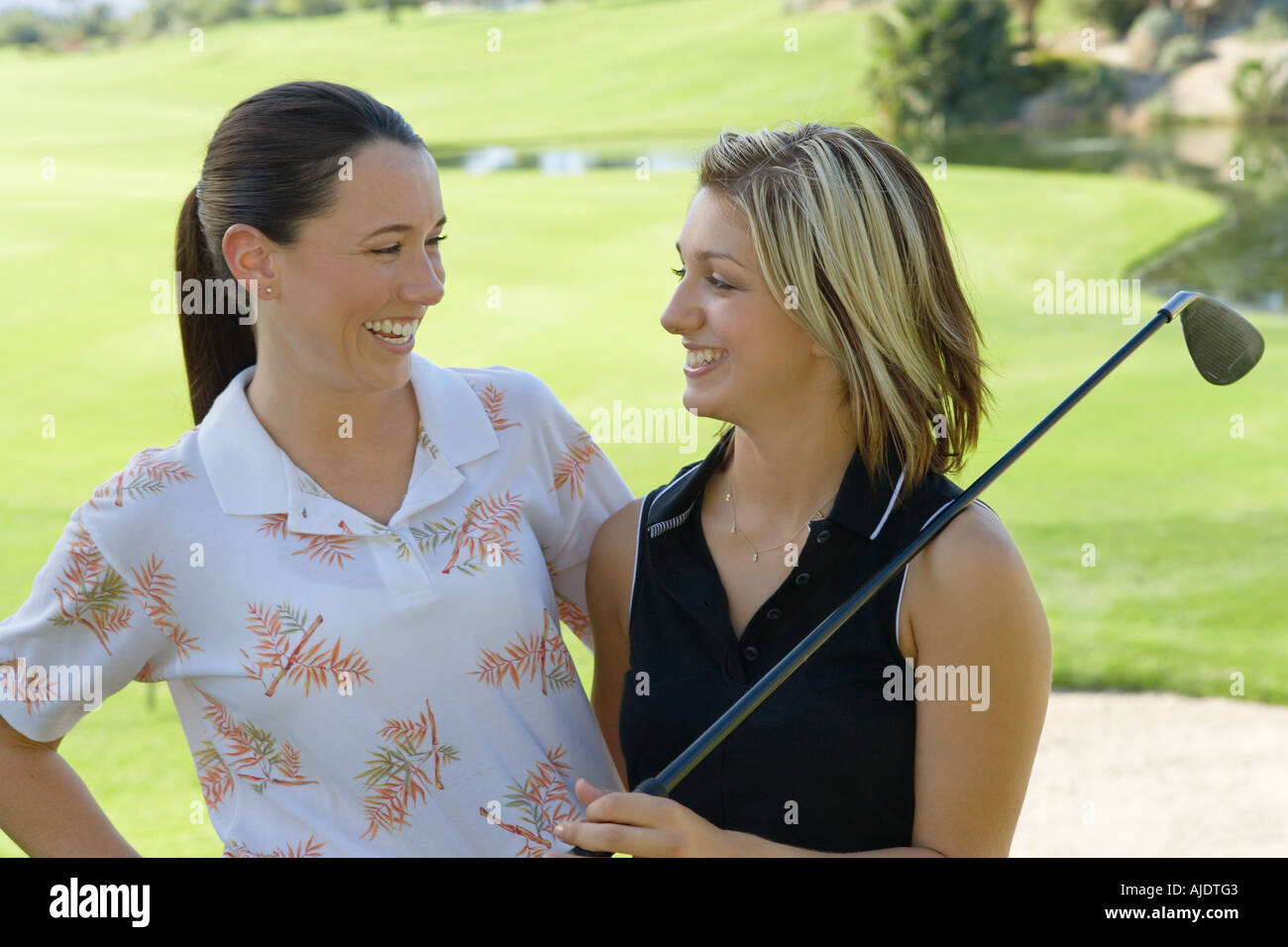 Two female golfers laughing to each other Stock Photo - Alamy