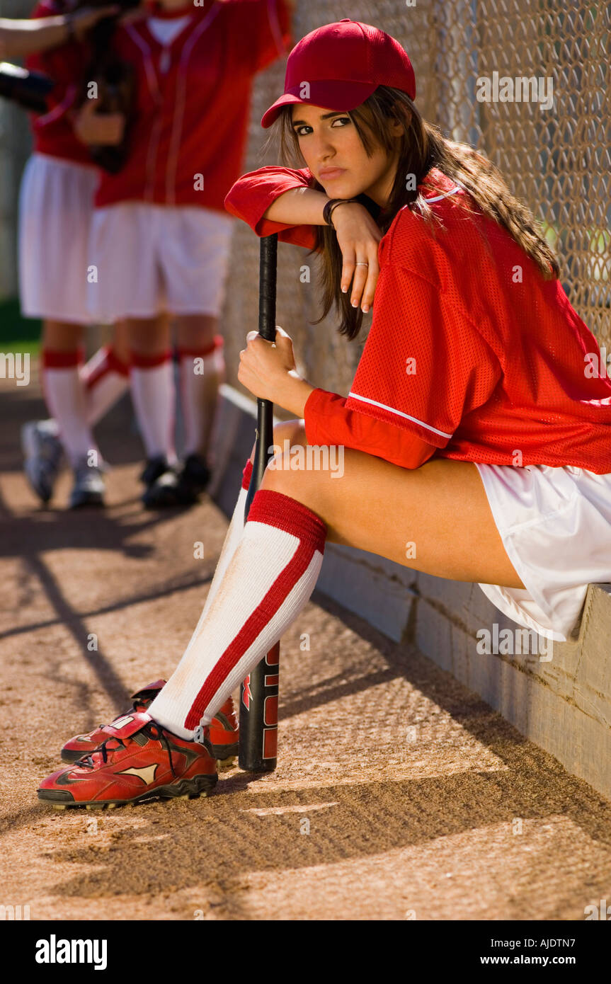 Softball player sitting on bench with bat, portrait Stock Photo - Alamy