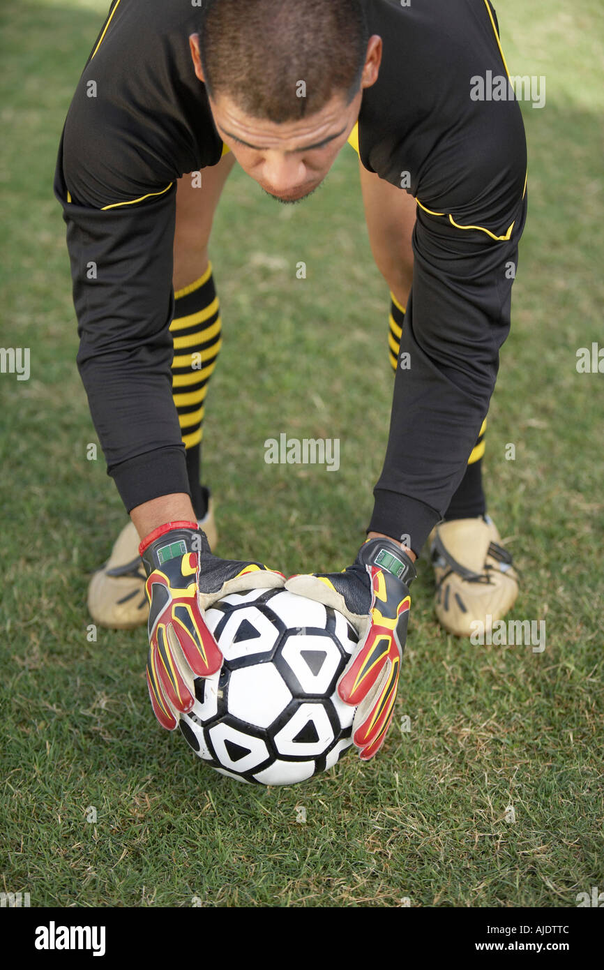 Goalkeeper bending down with ball, portrait Stock Photo - Alamy