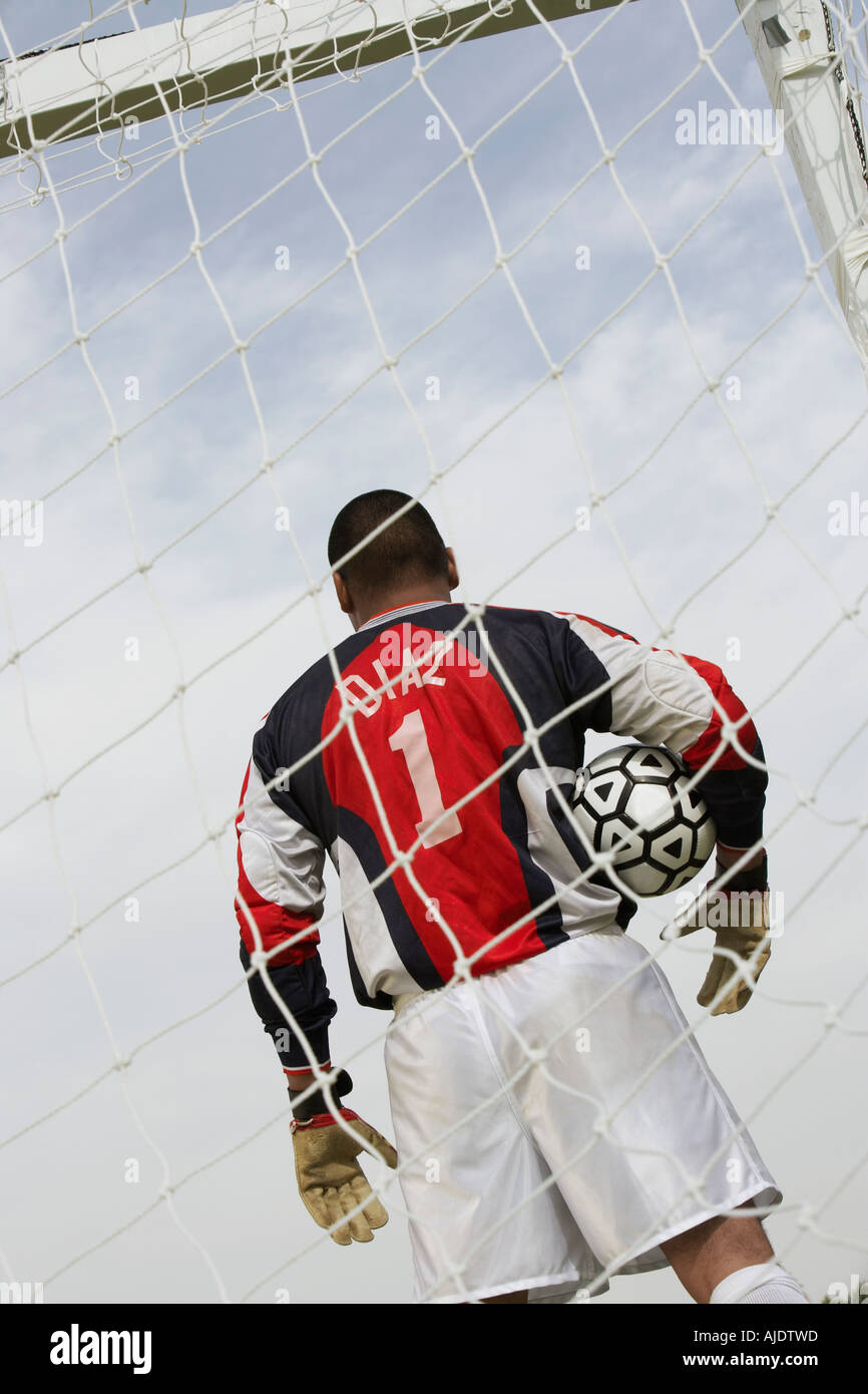 Goalkeeper standing in goal with ball, back view, low angle view Stock ...