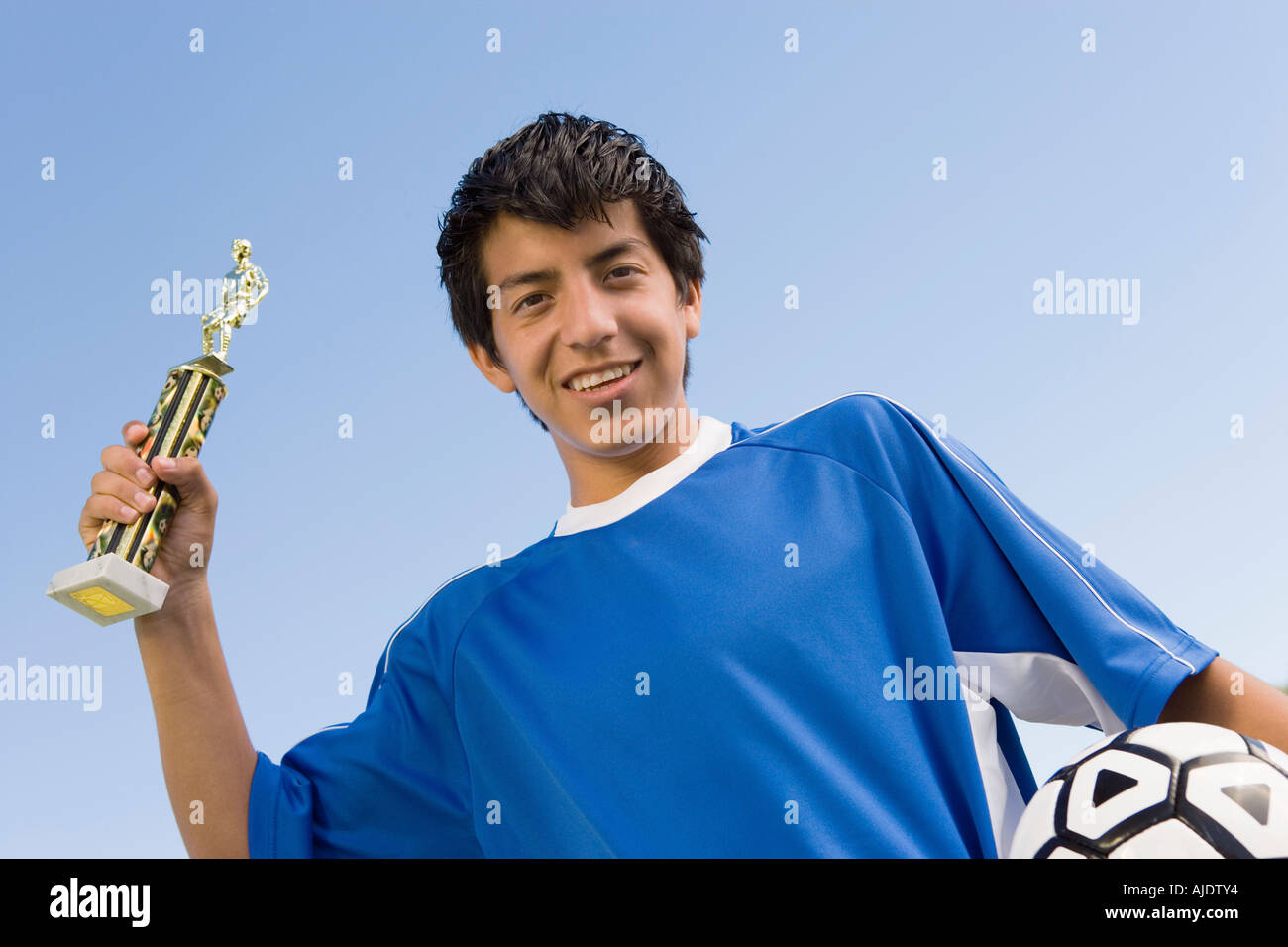 Soccer player holding trophy and ball, portrait Stock Photo - Alamy