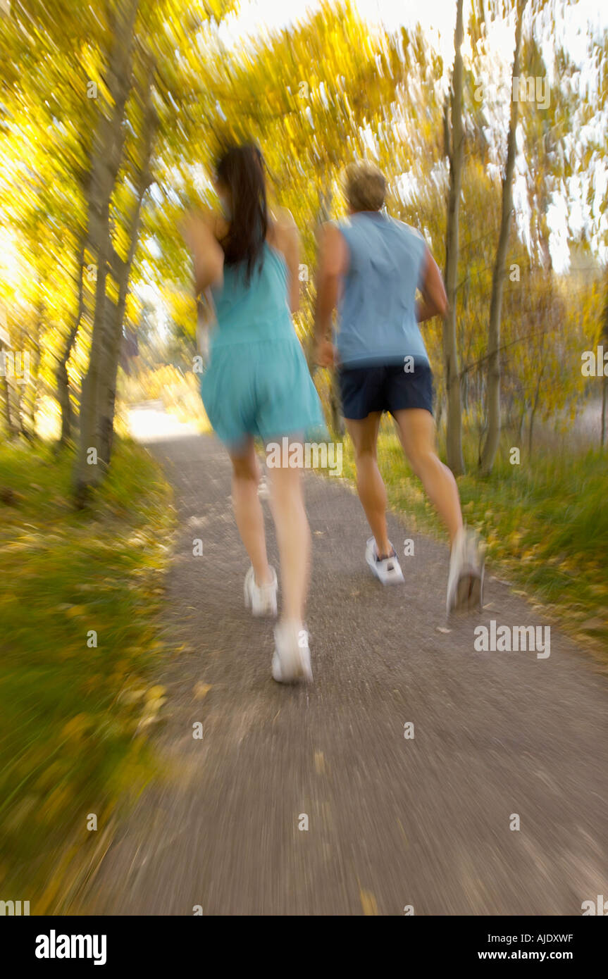 Couple jogging through woods, rear view Stock Photo - Alamy
