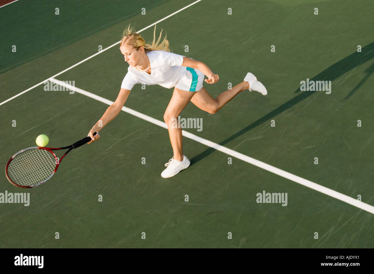 Tennis Player Reaching to hit tennis ball on tennis court Stock Photo ...
