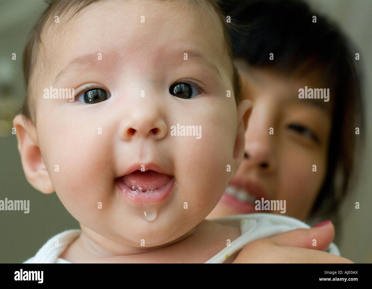 mother holding salivating baby both smiling eye contact Stock Photo - Alamy