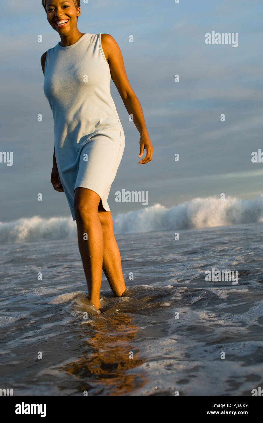 Woman walking through surf Stock Photo - Alamy
