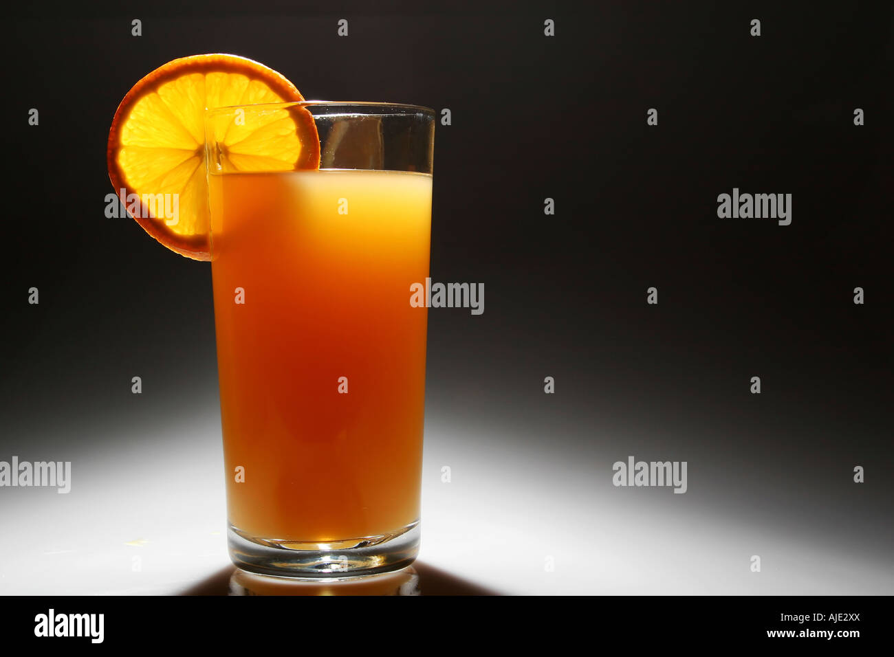 A Backlit glass of orange juice with a slice of orange Stock Photo - Alamy