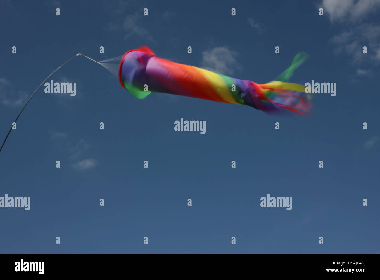 Colourful windsock blowing in the wind against a blue sky with white ...