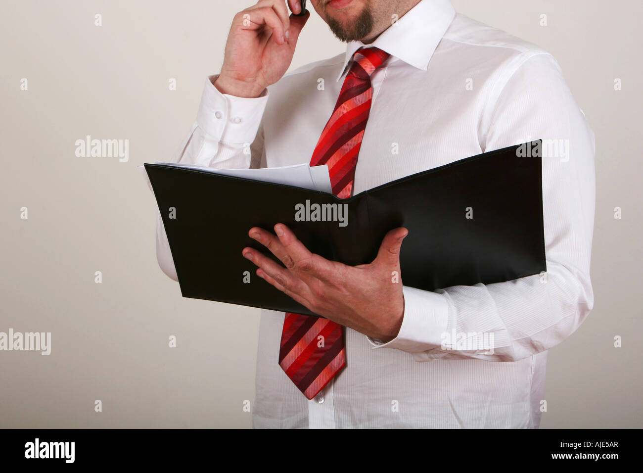 A cropped shot of a man in white shirt and tie reading report and ...