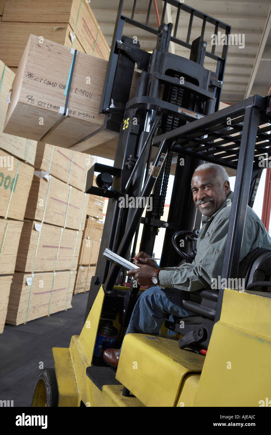 Man using forklift to lift box in warehouse Stock Photo - Alamy