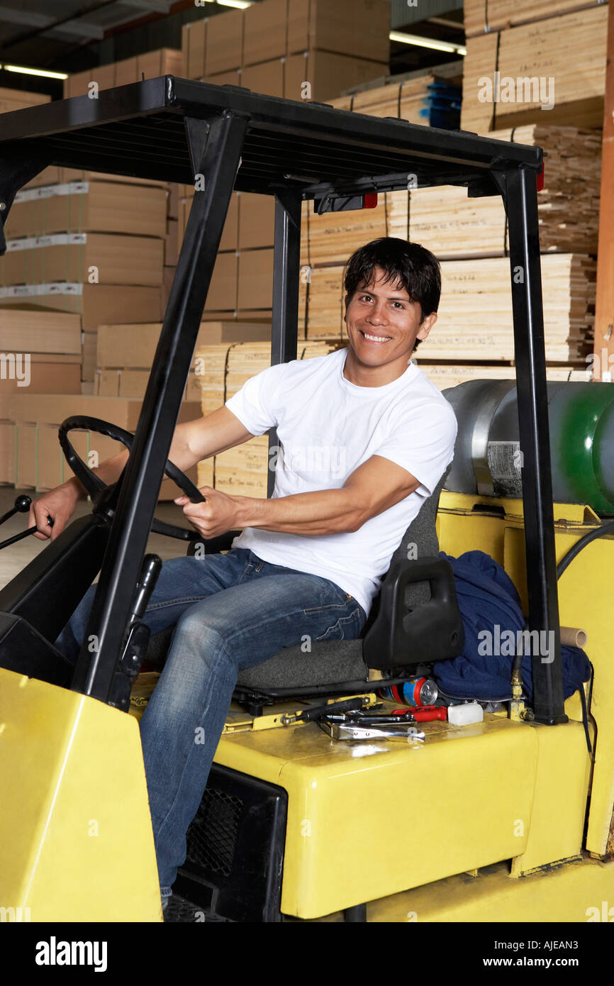Man driving forklift in warehouse full of wood Stock Photo - Alamy