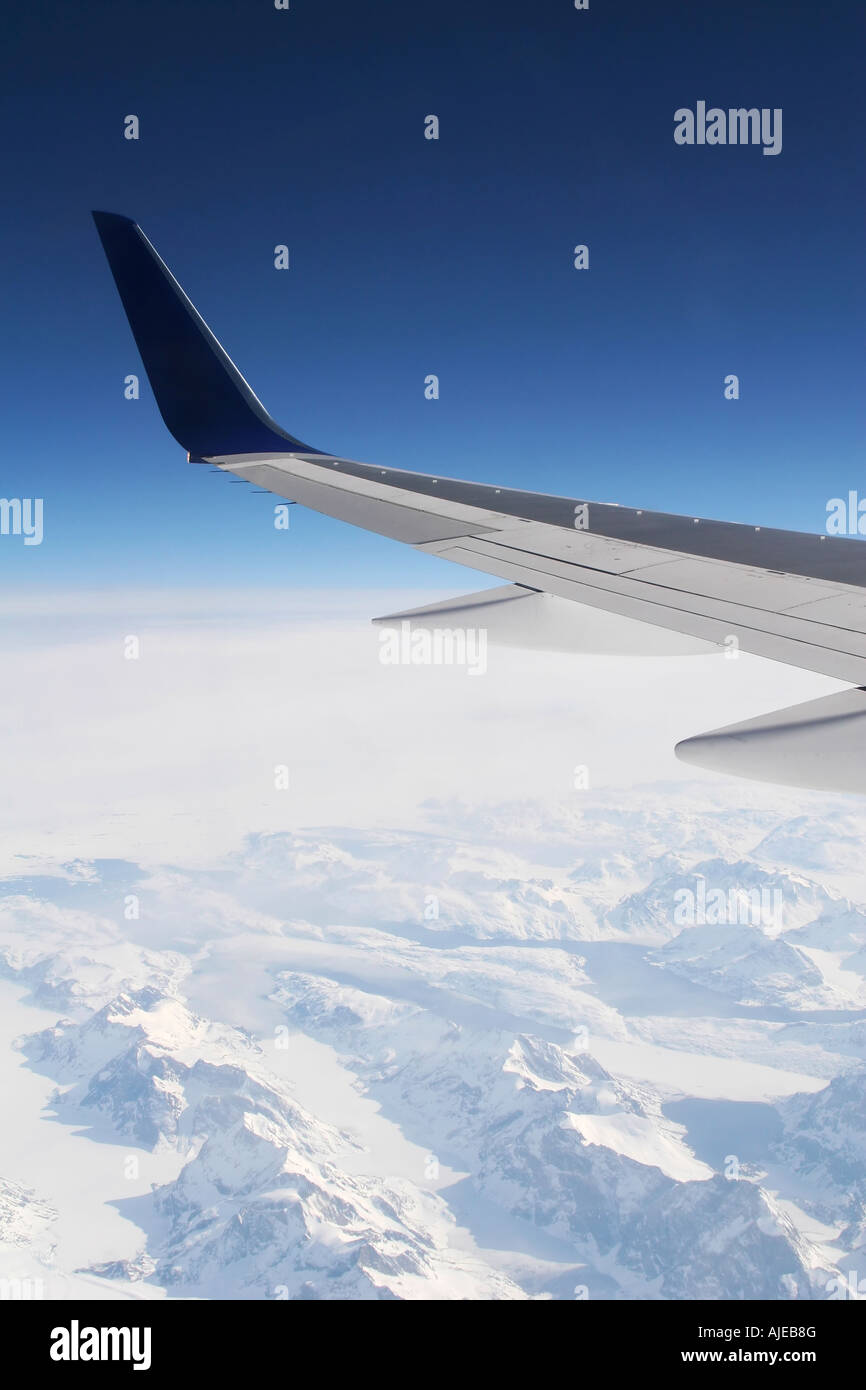 wing of a passenger jet at high altitude with snow covered mountain ...