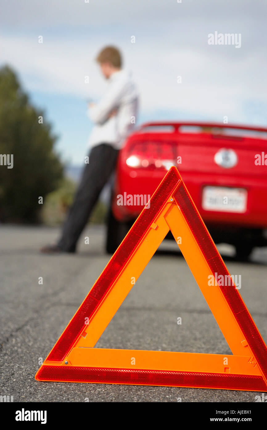 Warning triangle standing by man leaning on broken down car Stock Photo ...