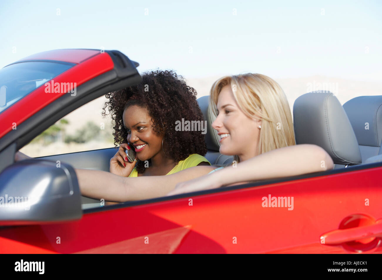 Two young women driving red convertible Stock Photo - Alamy
