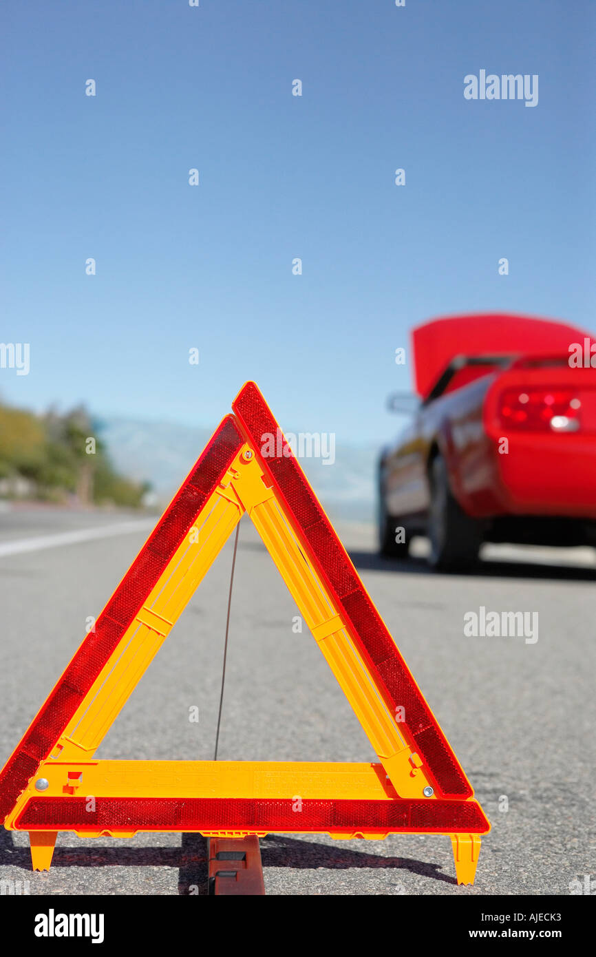 Warning triangle in front of broken down red sports car at side of road ...