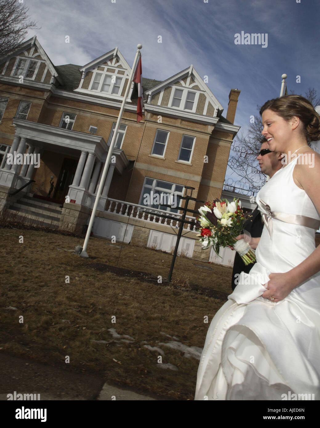 Bride and groom passing large brick building Stock Photo - Alamy