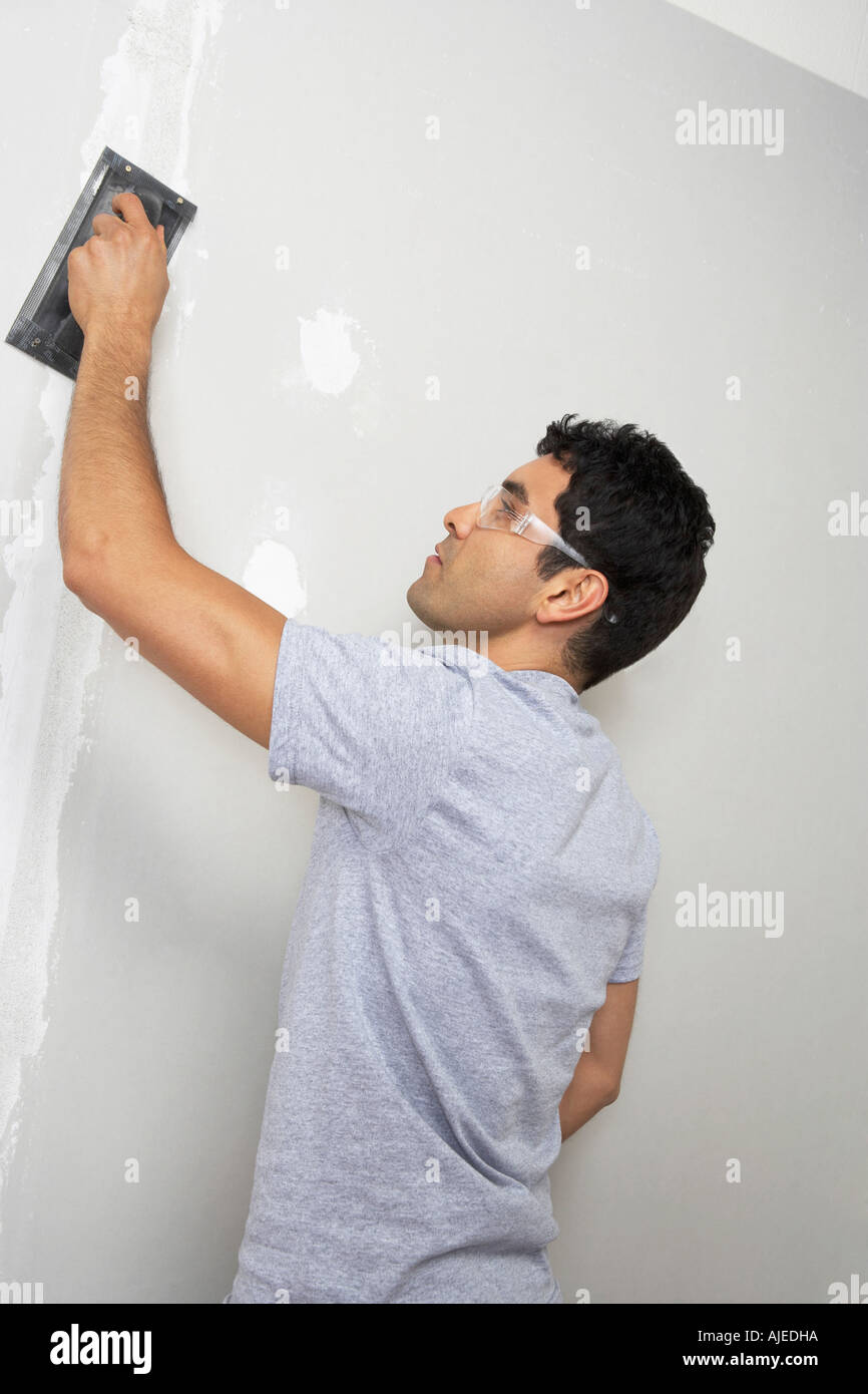 Man sanding interior wall Stock Photo - Alamy
