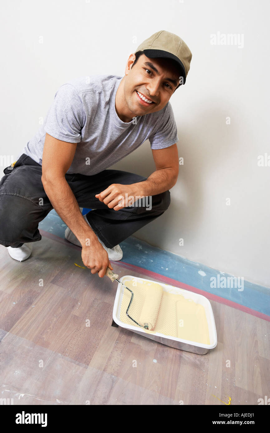 Man loading paint roller in tray indoors Stock Photo - Alamy