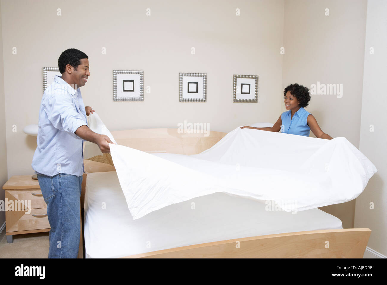 Couple making bed together Stock Photo - Alamy