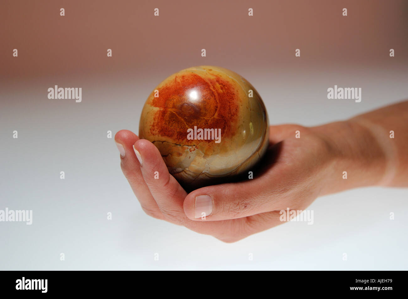 Large Mookaite sphere mineral specimen also known as yellow jasper held ...