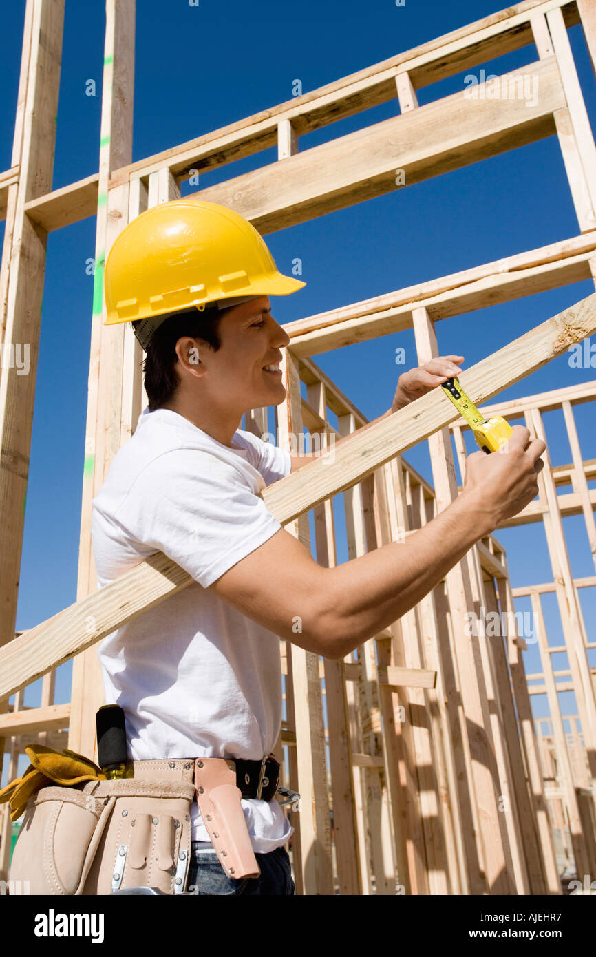 Construction worker measuring lumber at construction site Stock Photo ...