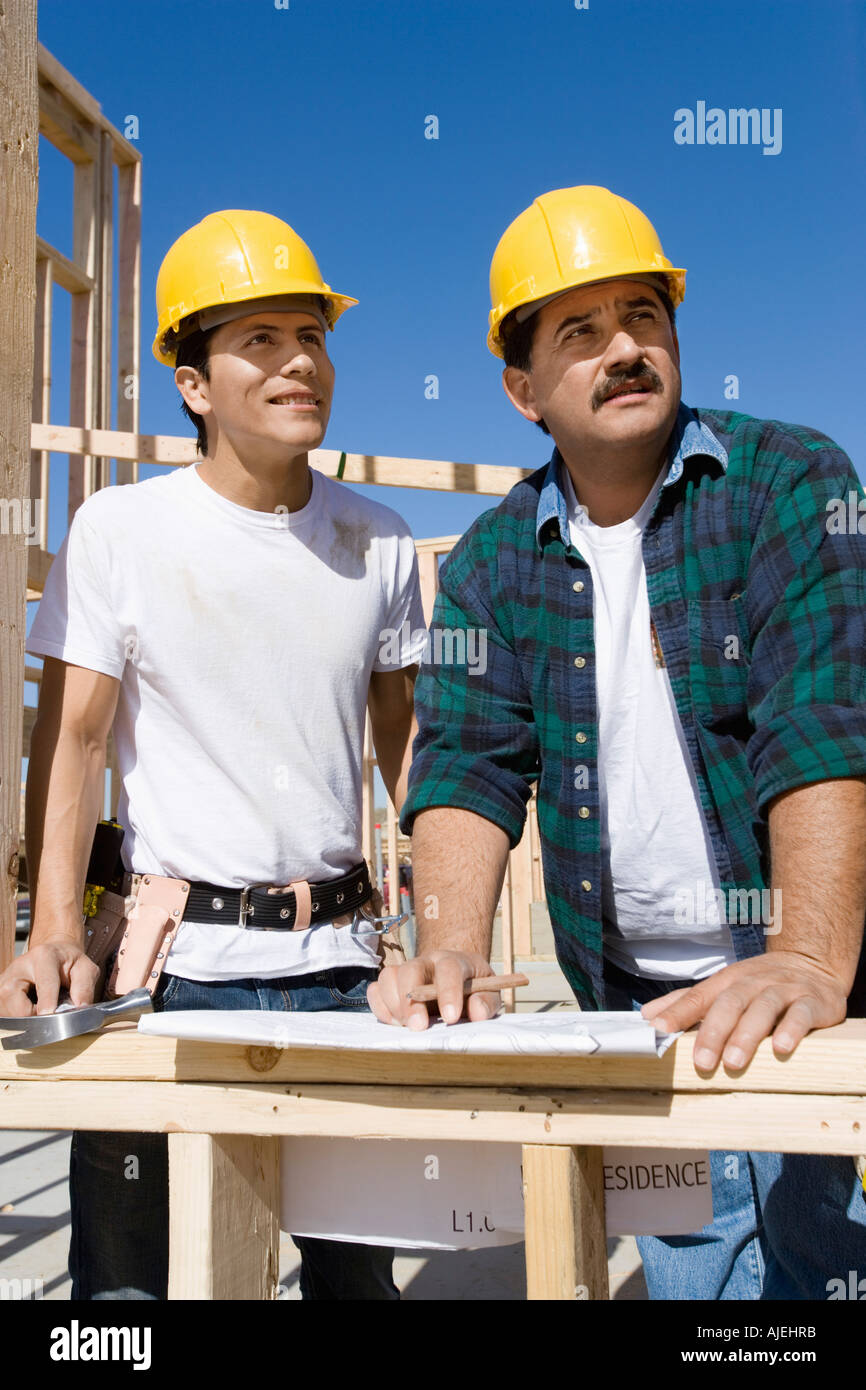 Two construction workers looking up, on construction site Stock Photo ...