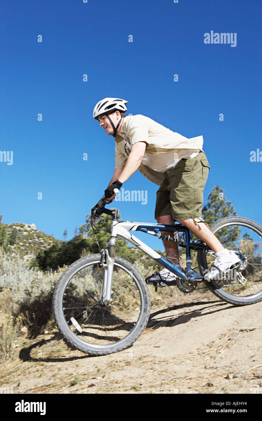 Young man mountain biking down track, side view Stock Photo - Alamy