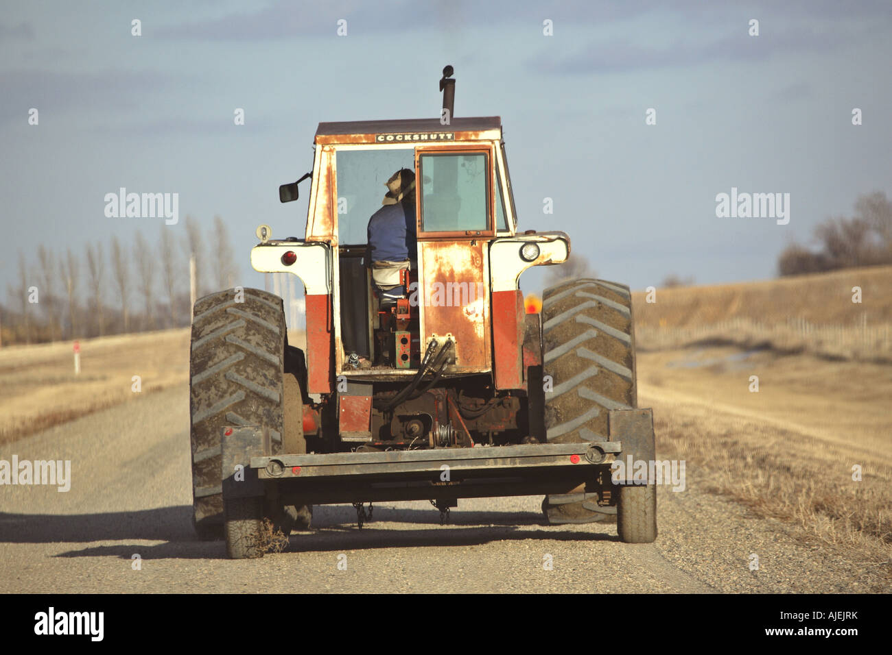 Farmer driving tractor down country road Stock Photo - Alamy