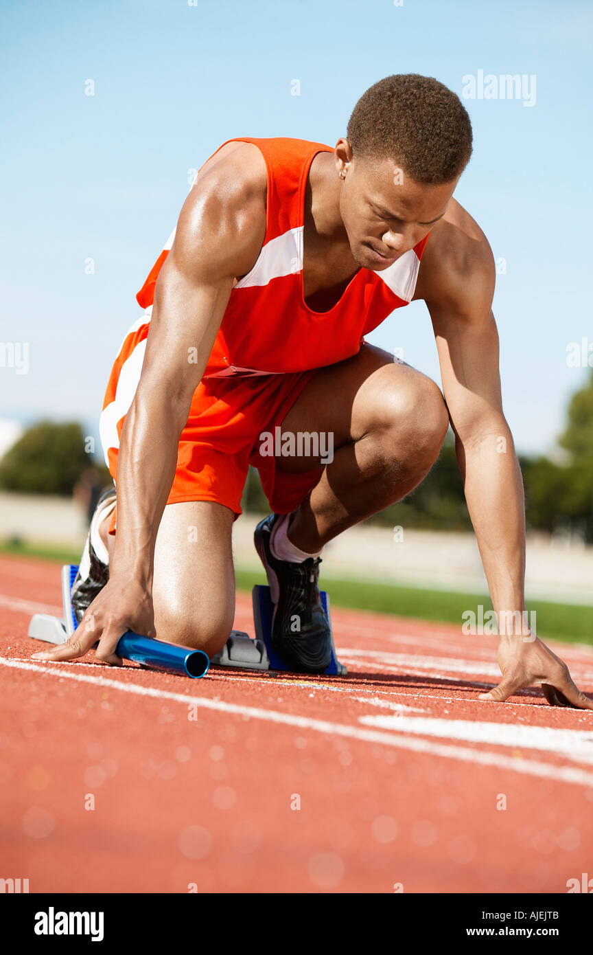 Runner Waiting in Starting Block holding Baton Stock Photo - Alamy