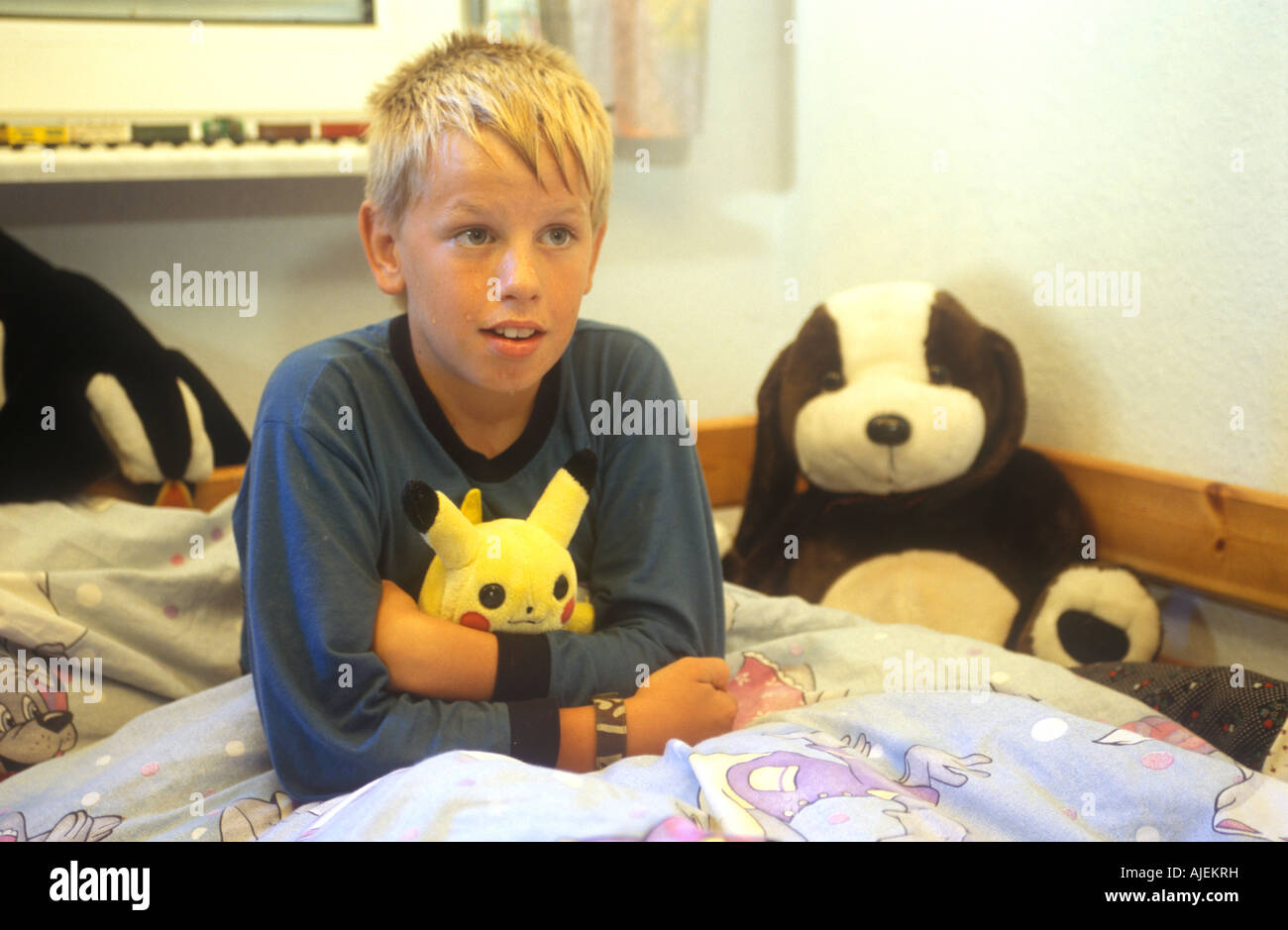 a scared young boy sitting in his bed sweating after waking up from a ...