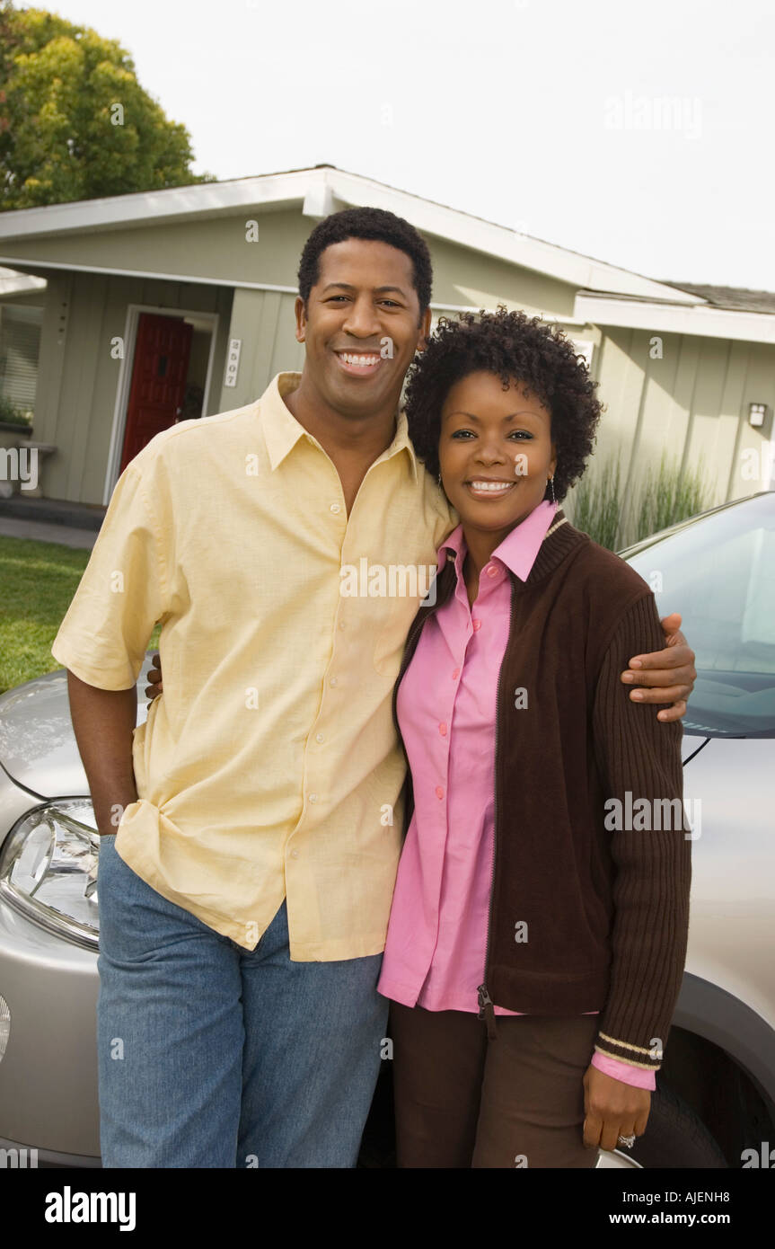 Couple standing by car in front of bungalow Stock Photo - Alamy