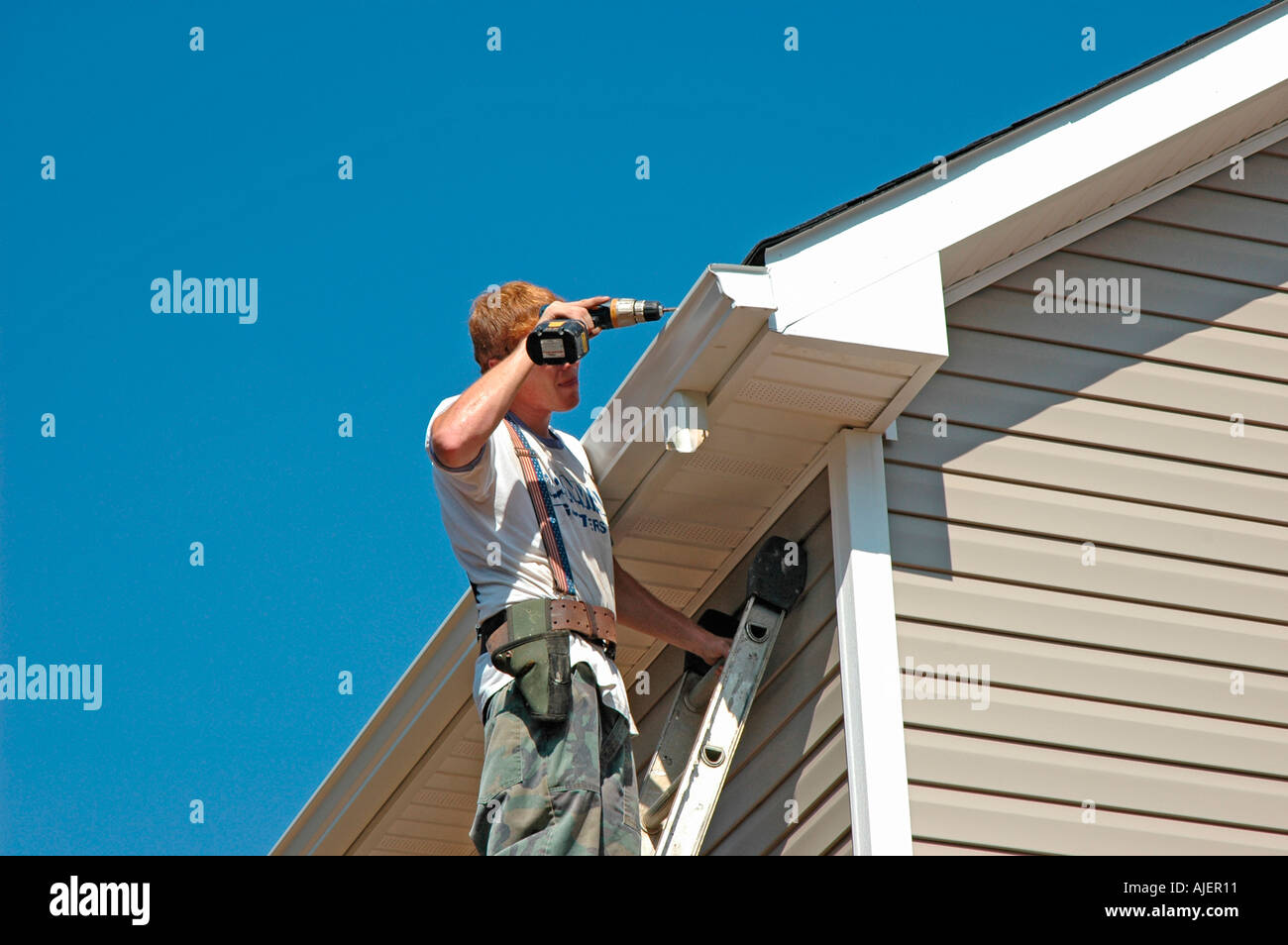 Installation of rain water run off gutters by young men on ladders and ...