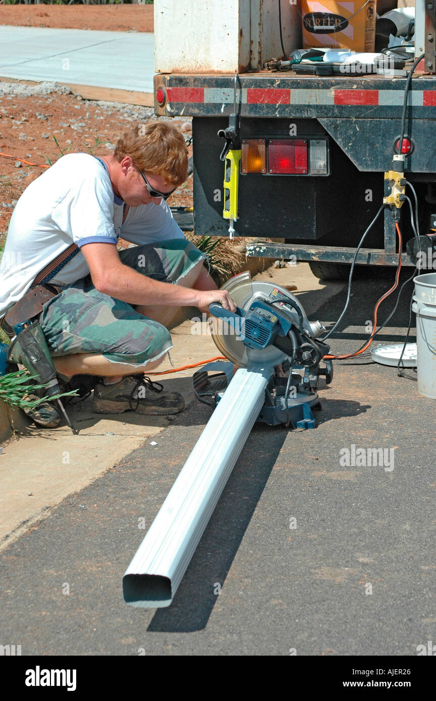 Installation of rain water run off gutters by young men on ladders and ...