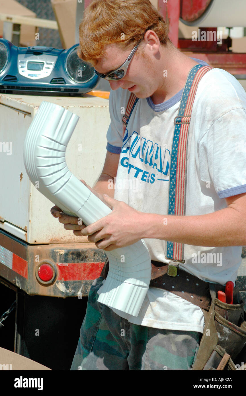 Installation of rain water run off gutters by young men on ladders and ...