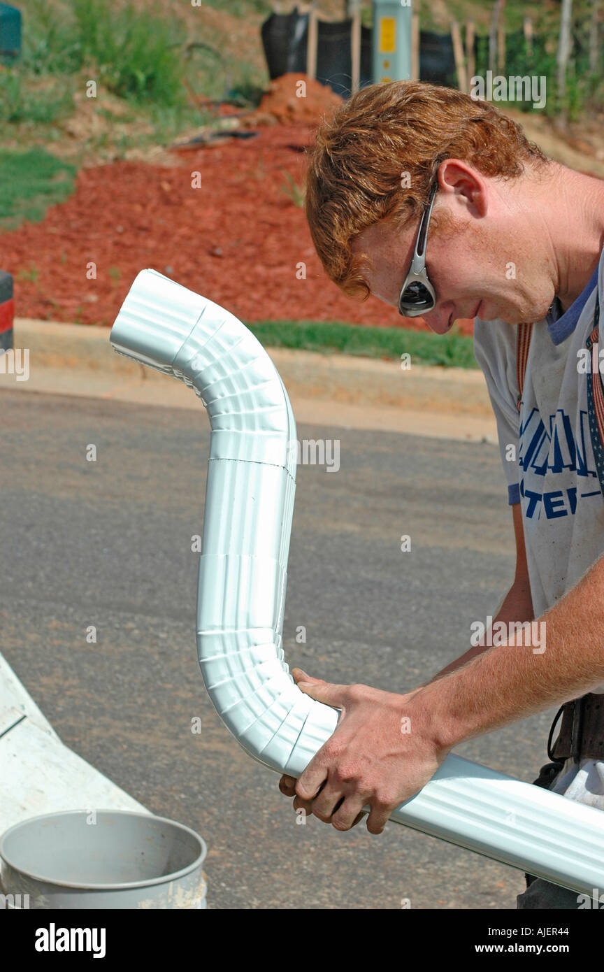 Installation of rain water run off gutters by young men on ladders and ...