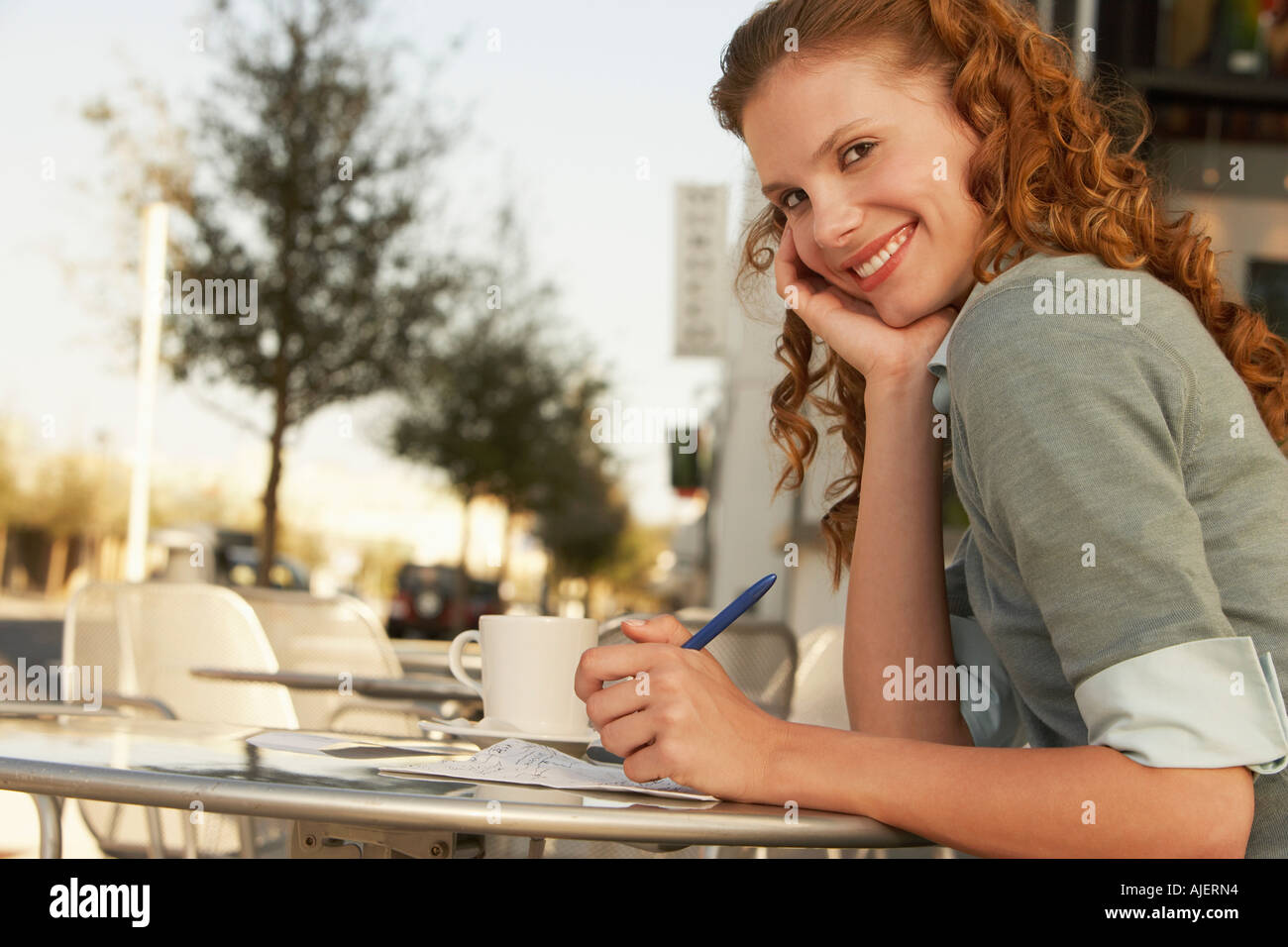 Young woman writing at outdoor cafe, portrait Stock Photo - Alamy