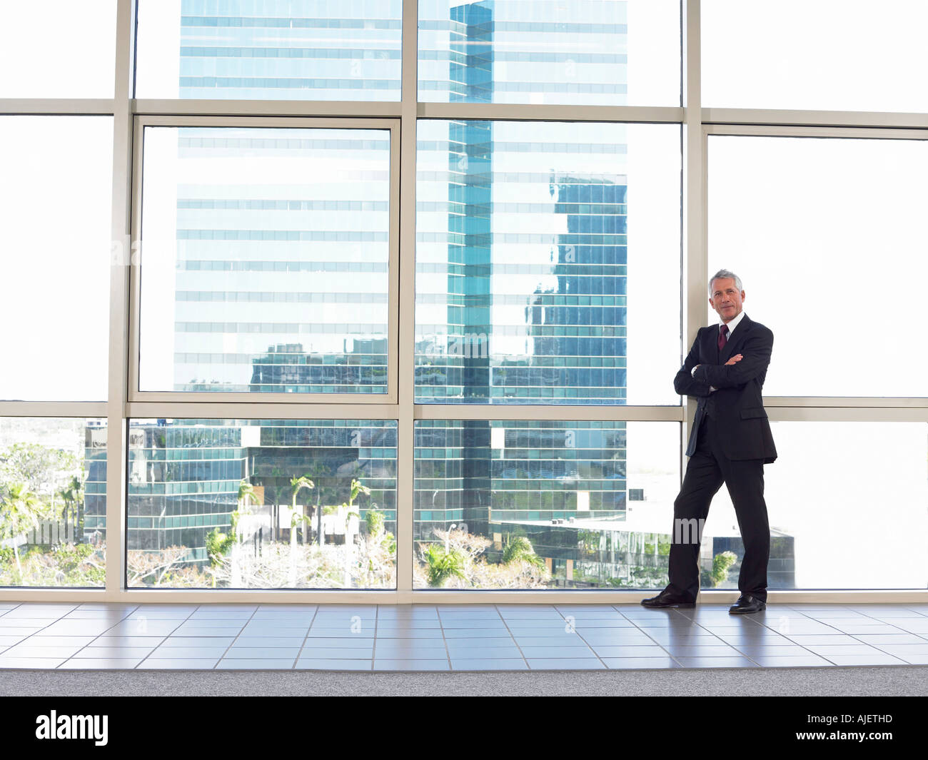 Businessman by window in office building, portrait Stock Photo - Alamy