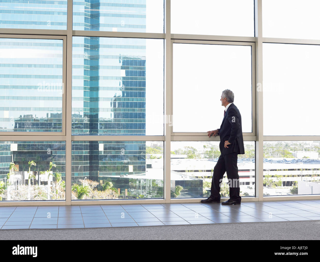Businessman looking out of office window Stock Photo - Alamy