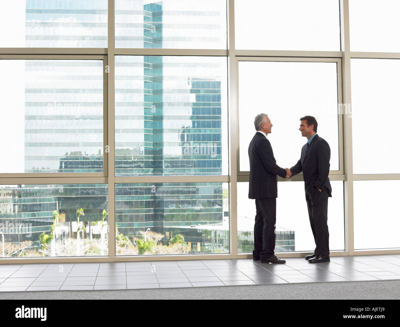 Businessmen shaking hands in office building Stock Photo - Alamy