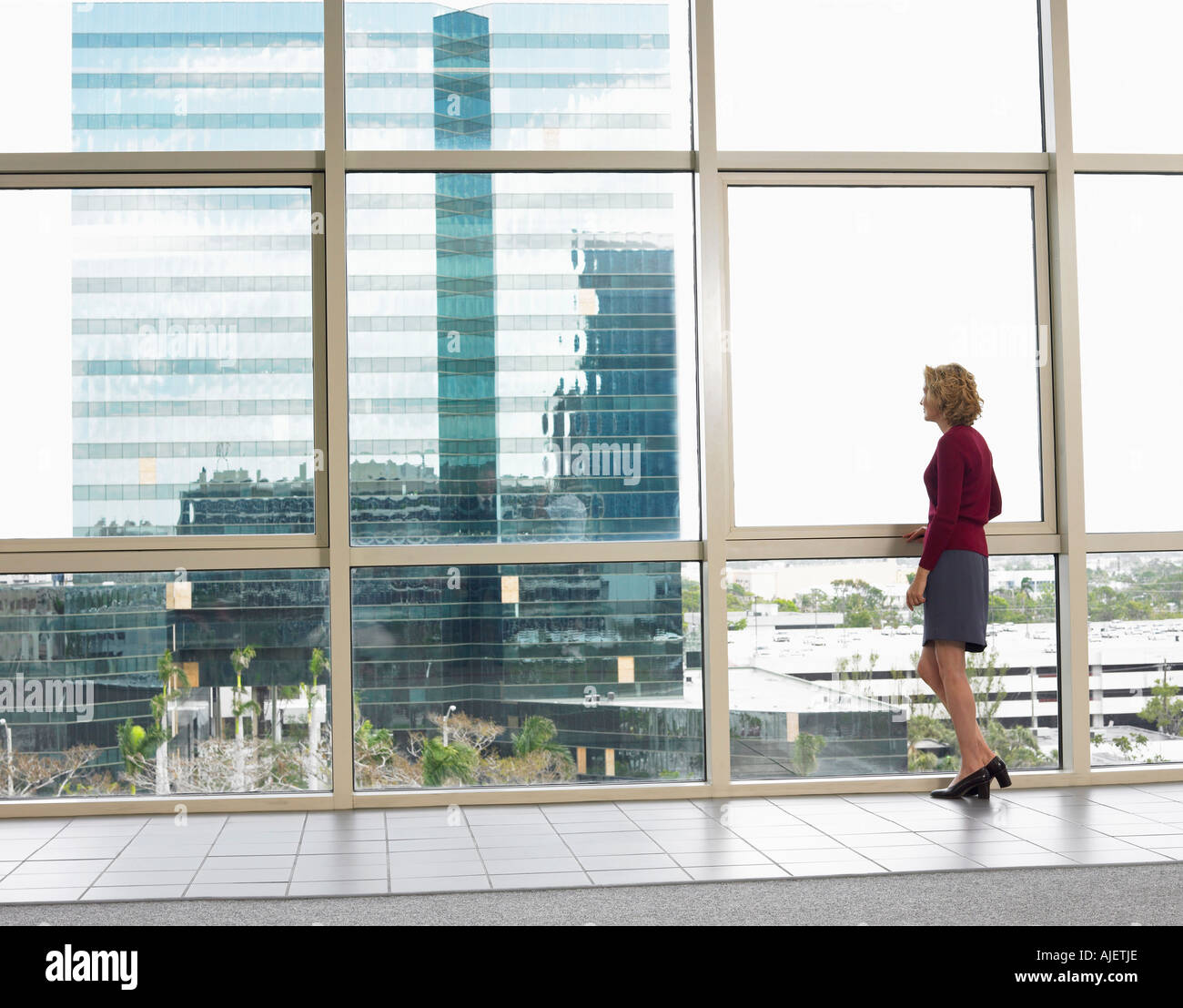 Businesswoman looking out of office window Stock Photo - Alamy