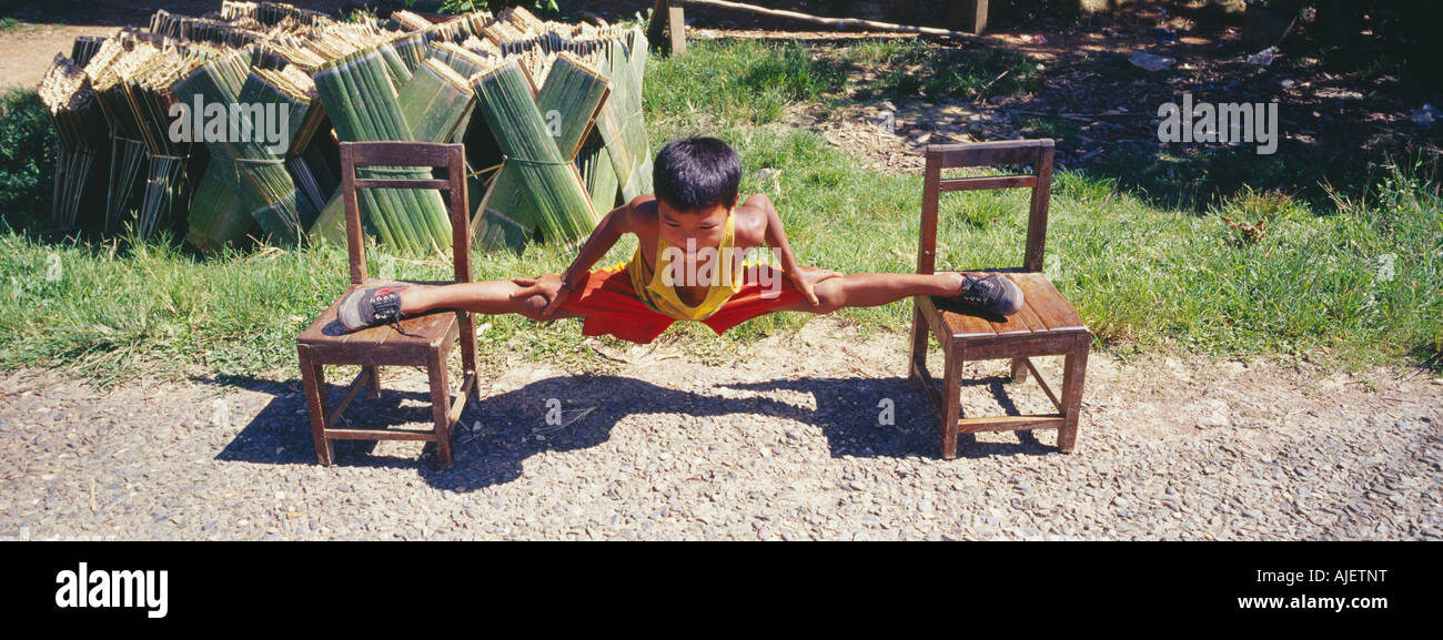 young boy doing splits on chairs, Laos Stock Photo - Alamy