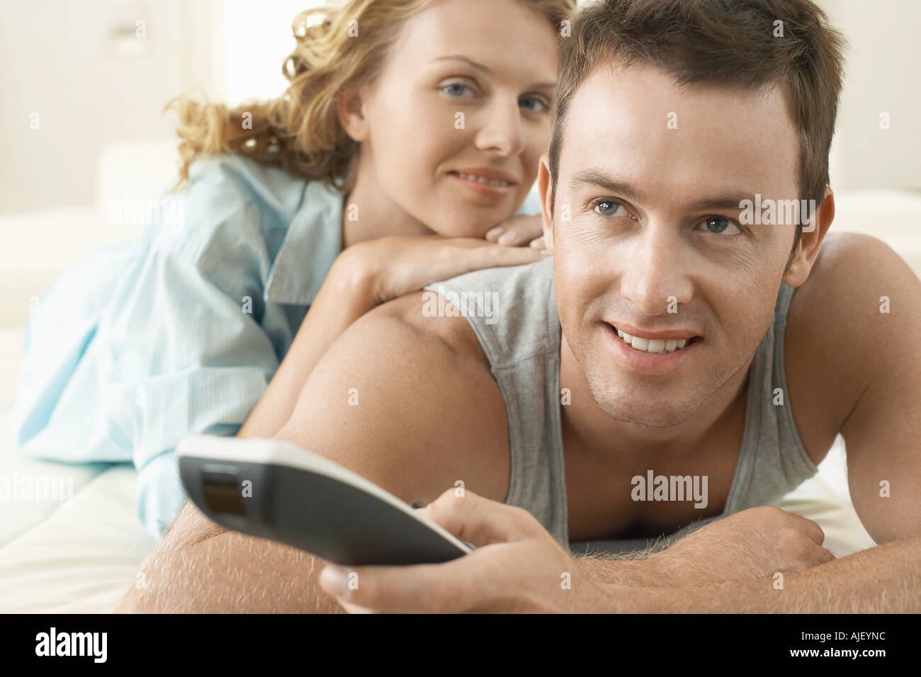 Couple on bed relaxing together, man holding remote control Stock Photo ...