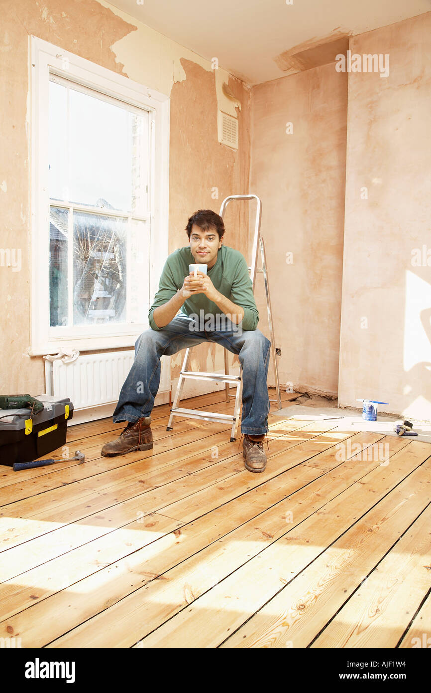 Man sitting on step ladder in unrenovated room Stock Photo - Alamy