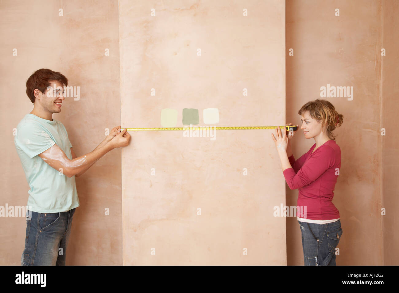 Couple holding measuring tape to wall in unrenovated room Stock Photo ...
