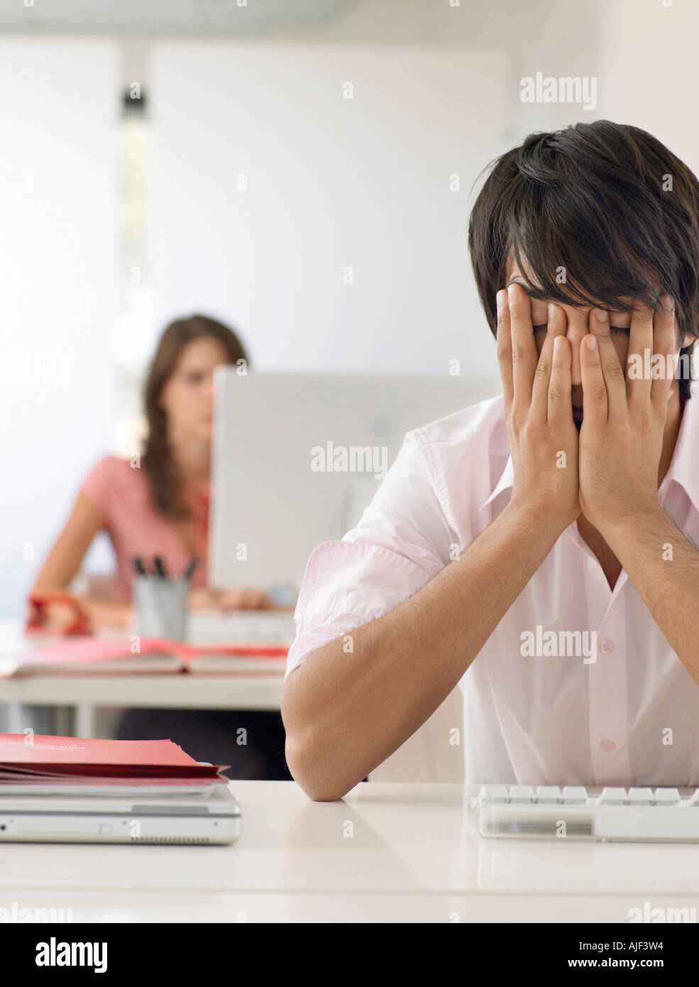 Business man at desk with head in hands Stock Photo - Alamy