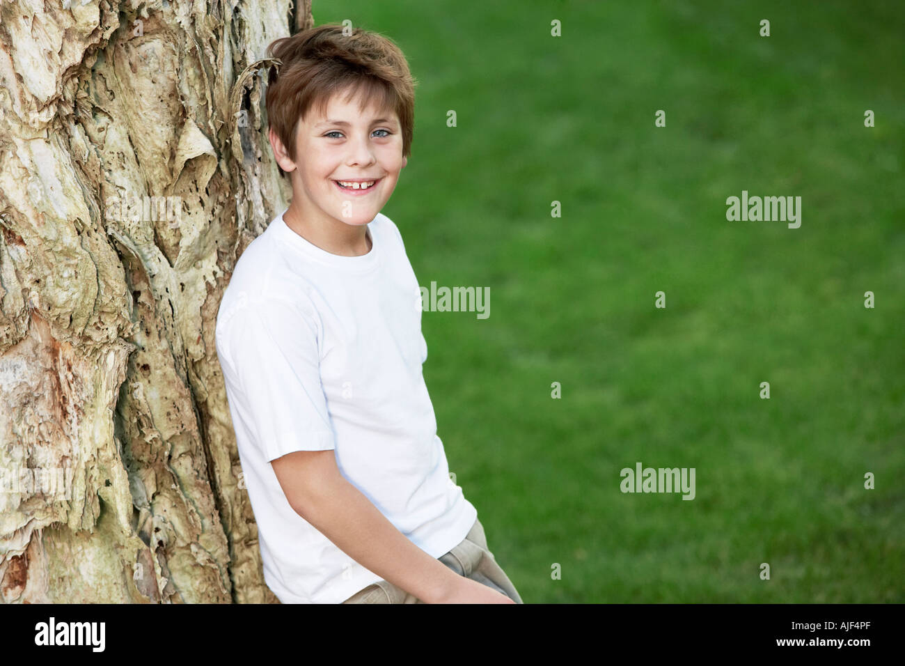 Boy leaning against tree, portrait Stock Photo - Alamy
