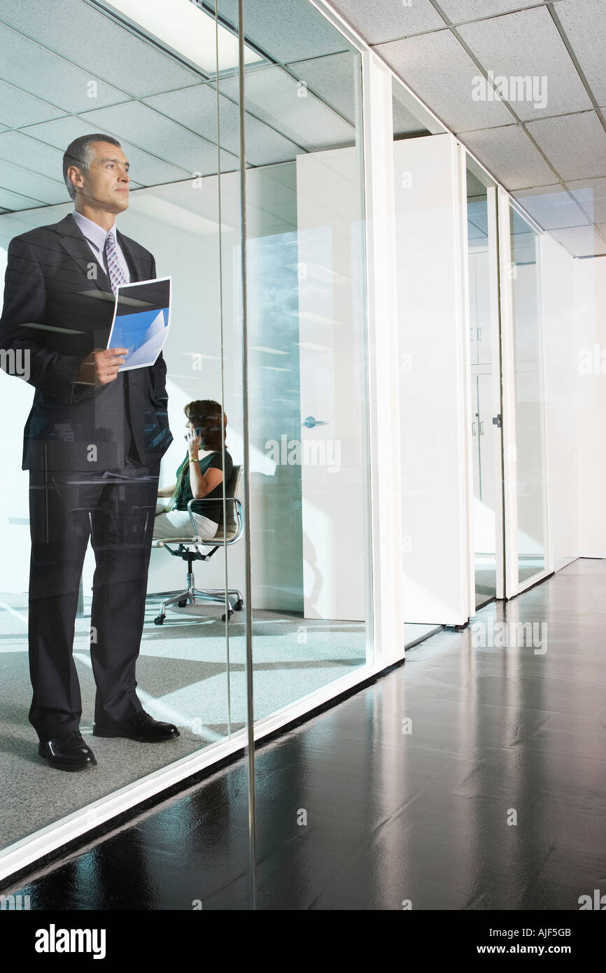 Businessman standing behind glass wall in office interior Stock Photo ...