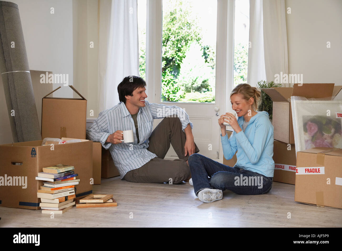 Couple taking a break among moving boxes Stock Photo - Alamy