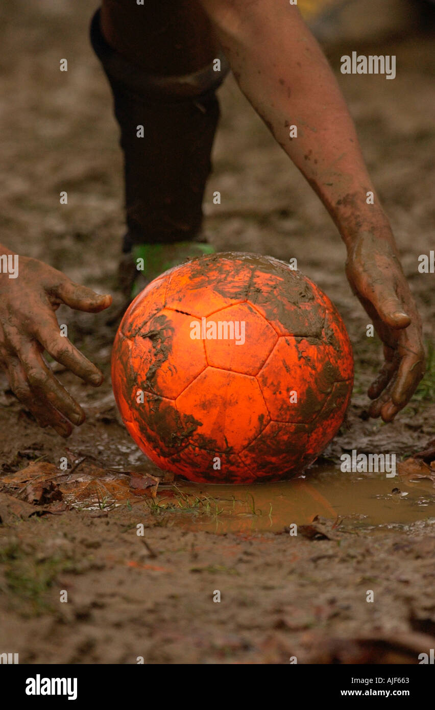 Orange football being picked up from a mud puddle Stock Photo - Alamy