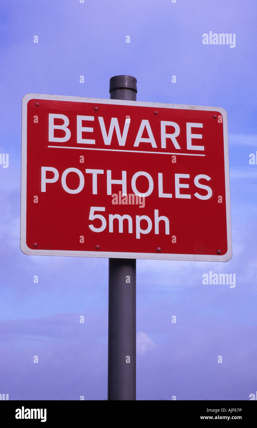 warning sign of potholes in road surface uk Stock Photo - Alamy